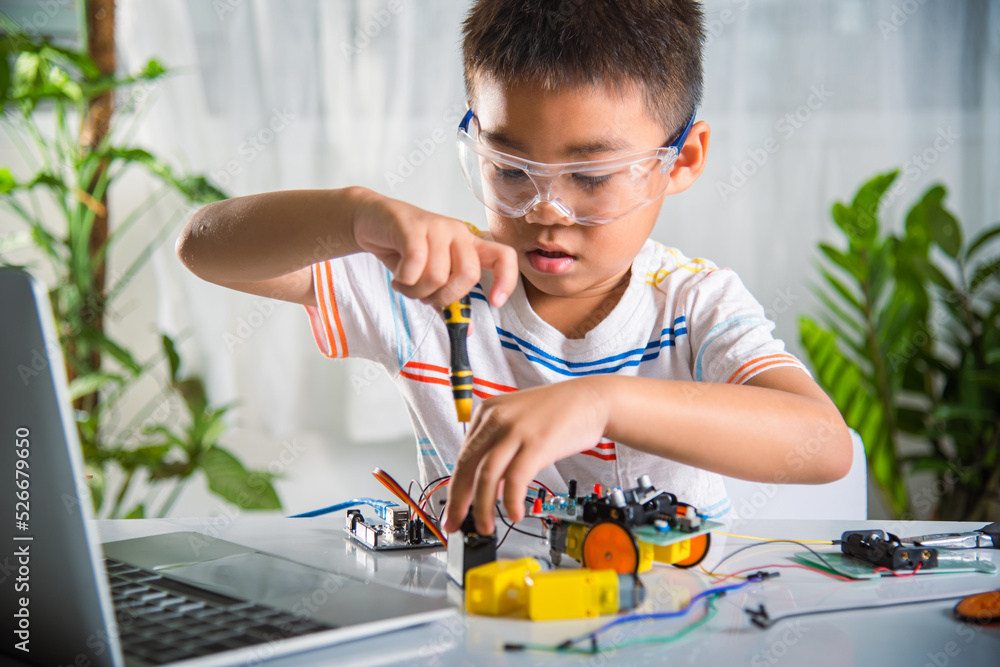 Asian kid boy assembling the Arduino robot car homework project at home ...
