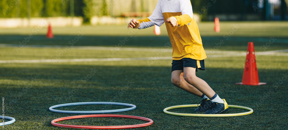 Foto de Little boy jumping over obstacles hula hoops on kids sports ...