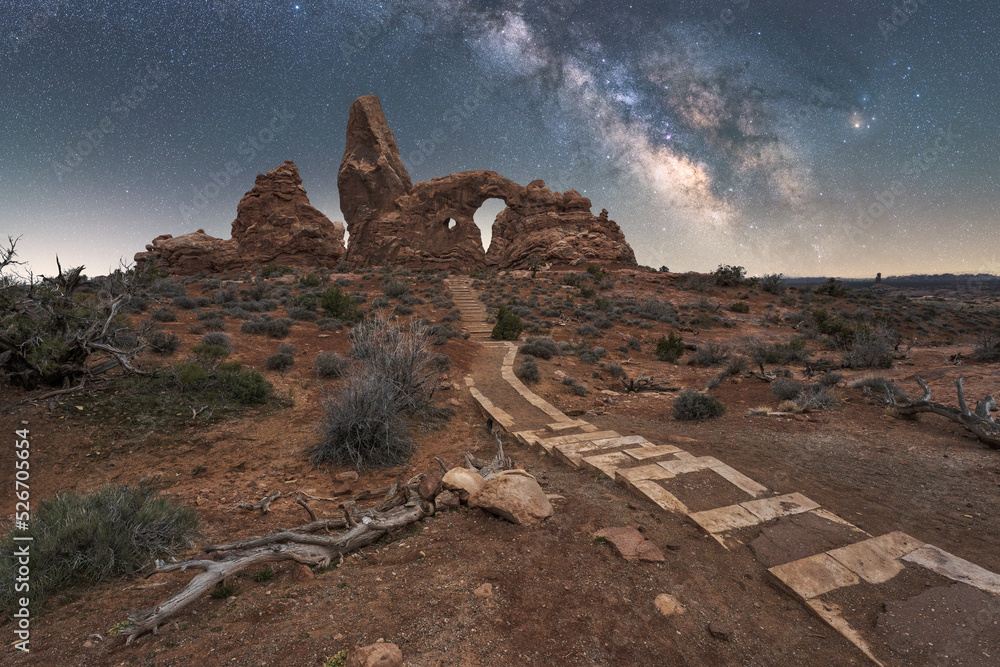 Steps leading to natural stone arch and canyon under starry sky with ...