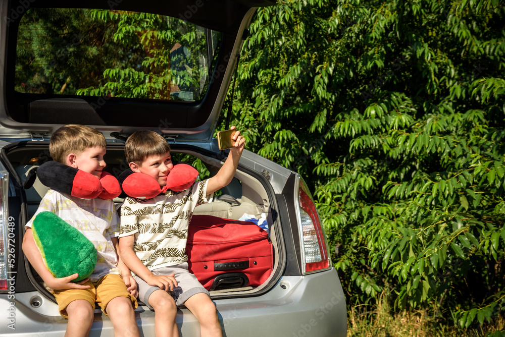 Two adorable little kids boy sitting in car trunk just before leaving ...