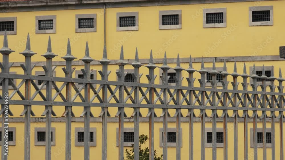 Yellow prison building wall with barred windows of prison cells behind ...