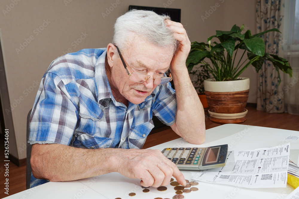 Foto de Upset depressed Senior man sitting at the table and calculating ...