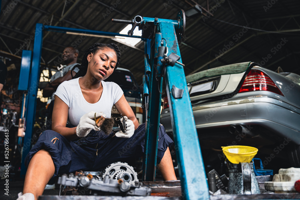 Professional mechanic wearing gloves is using brush to clean the engine ...