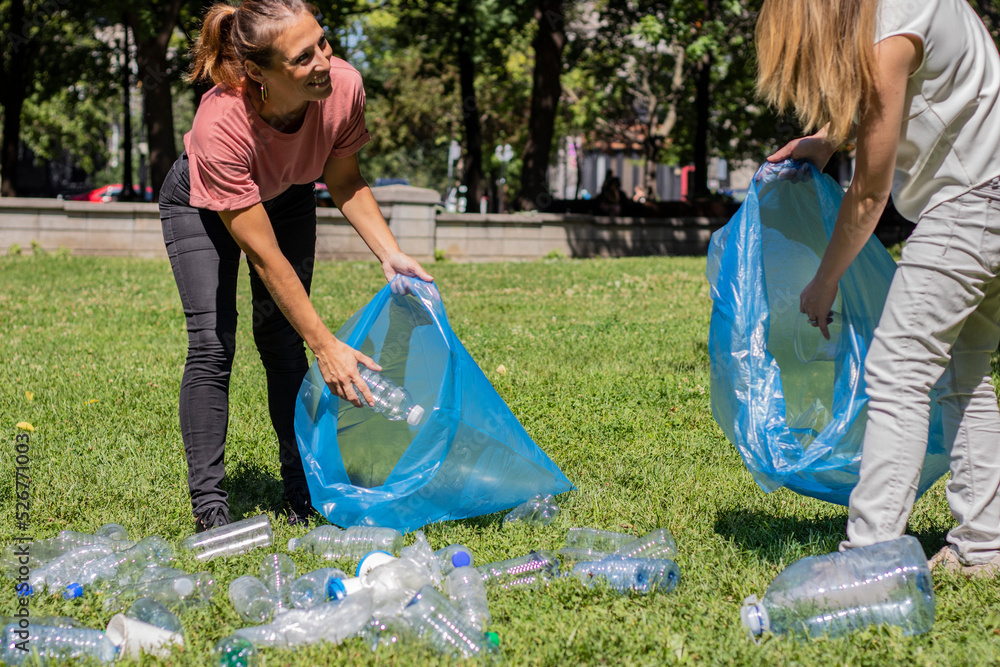 Beautiful Caucasian and Asian women collecting plastic bottles in a ...