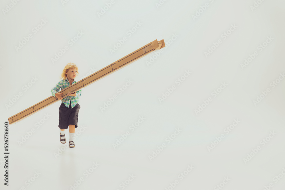 Portrait of little boy, child carrying giant long box isolated over ...