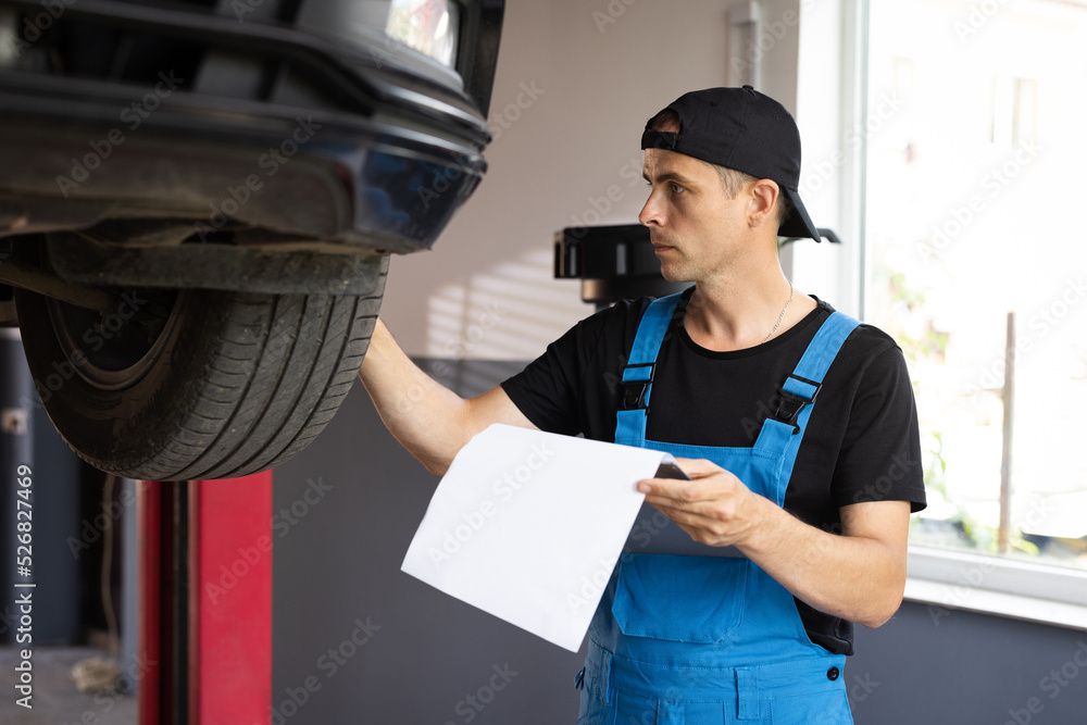 Car service employe inspect car. Mechanic inspects the car ...