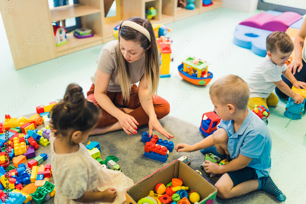Playtime at nursery school. Toddlers with their teacher sitting on the ...