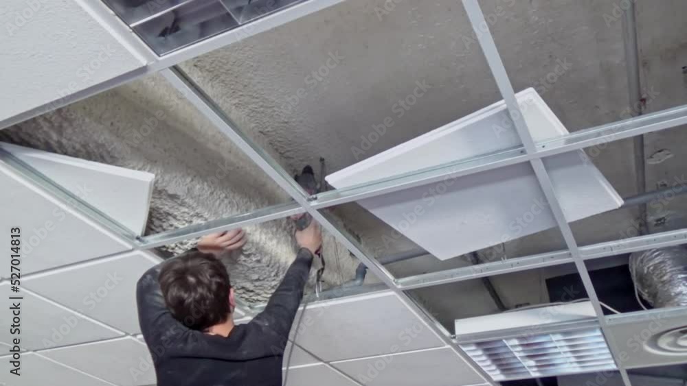 Construction worker performs a suspended ceiling maintenance with ...