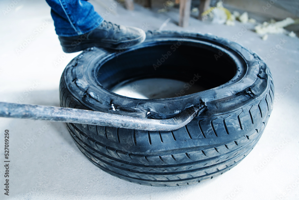 Strength test of car tires. A man tries to break rubber with a metal ...