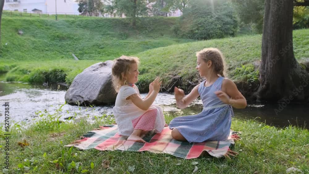 two teenage girls play with each other clapping their hands while ...