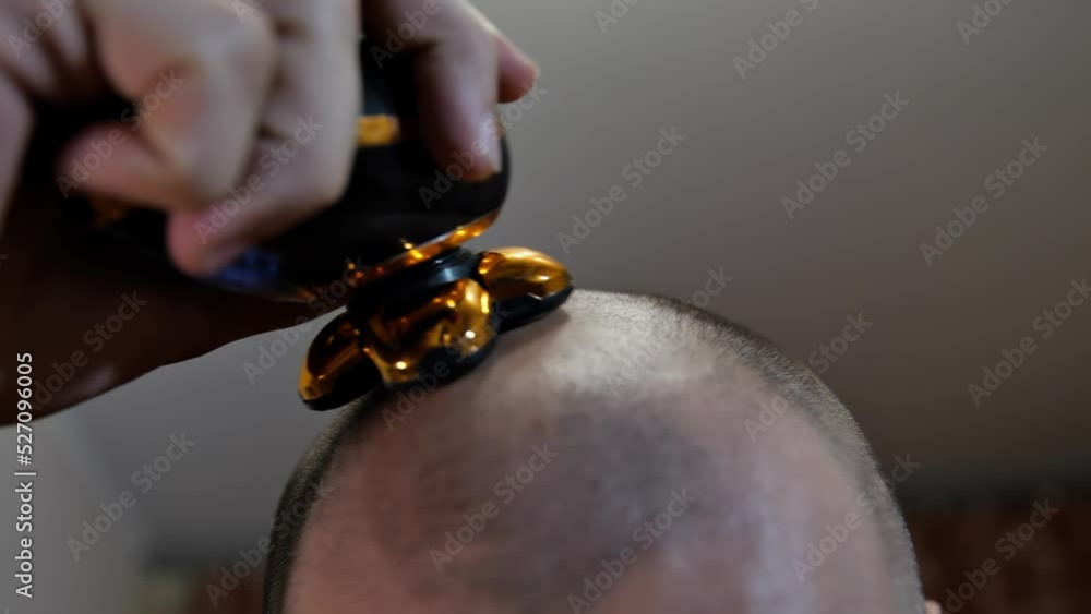 Close-up of the head of a bald man who shaves his bald head with an ...