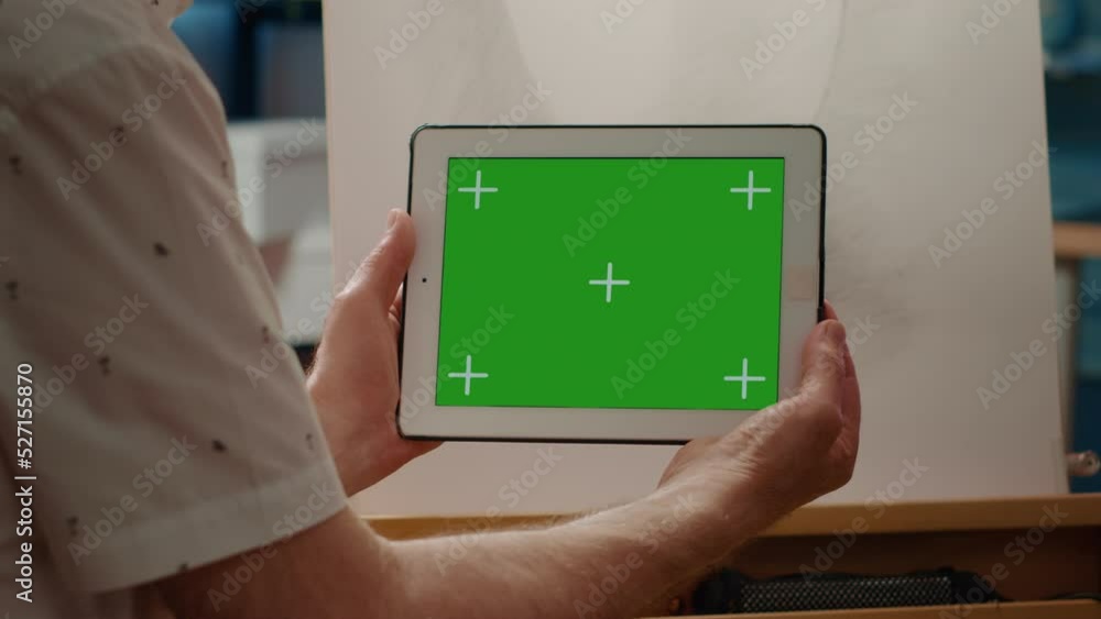 Creative artist looking at horizontal greenscreen on digital tablet to ...