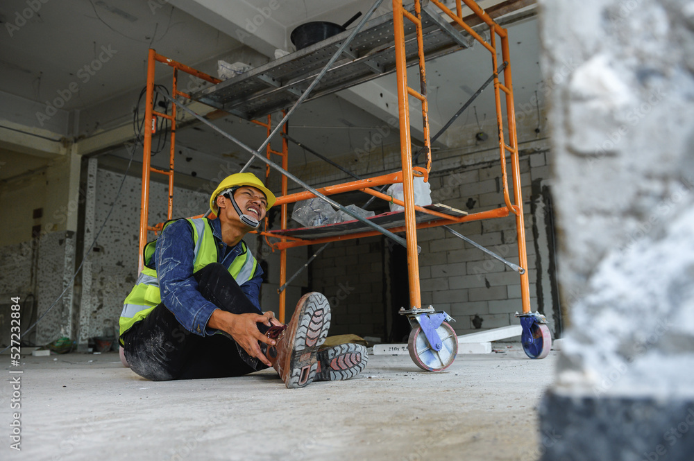 Construction worker sitting with ankle pain on the floor, ankle sprain ...