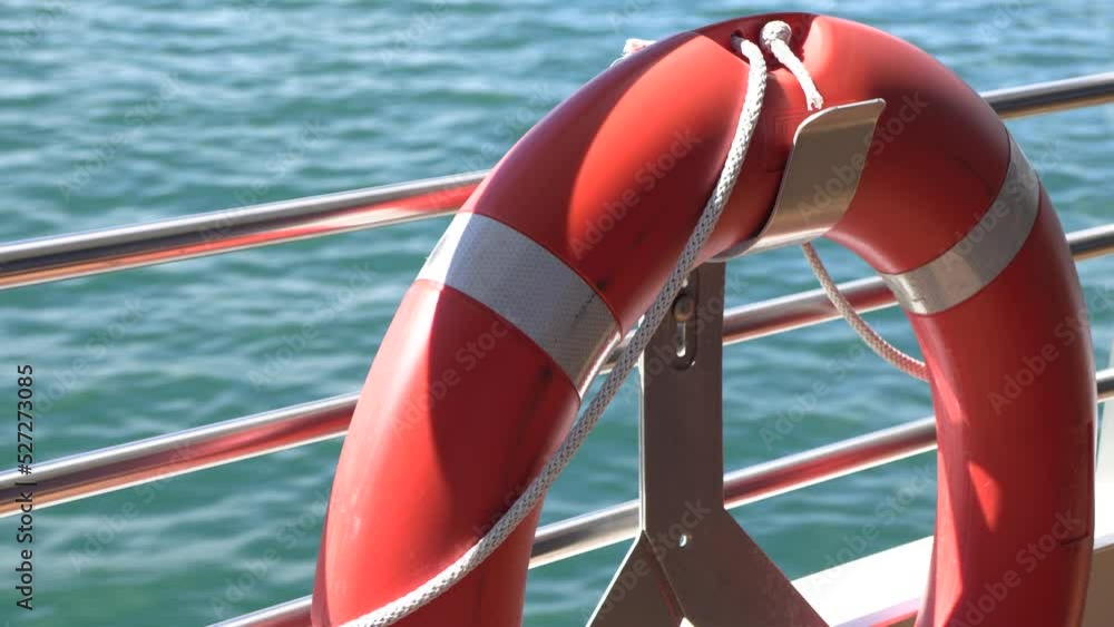 red and white life ring attached to a metal ship railing, in the ...