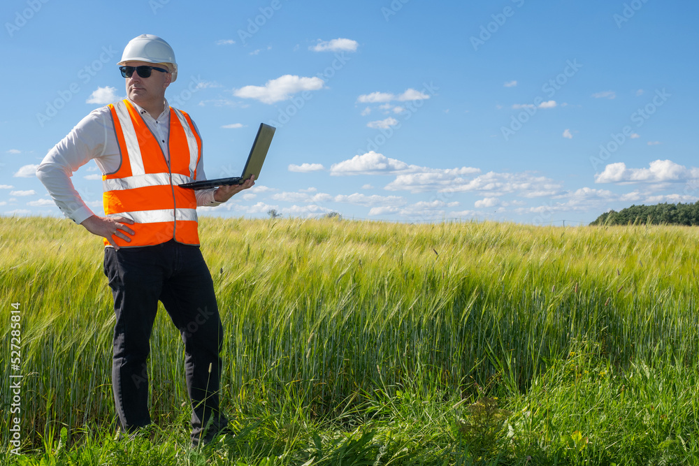 Engineer with laptop on green field. Man works for engineering company ...