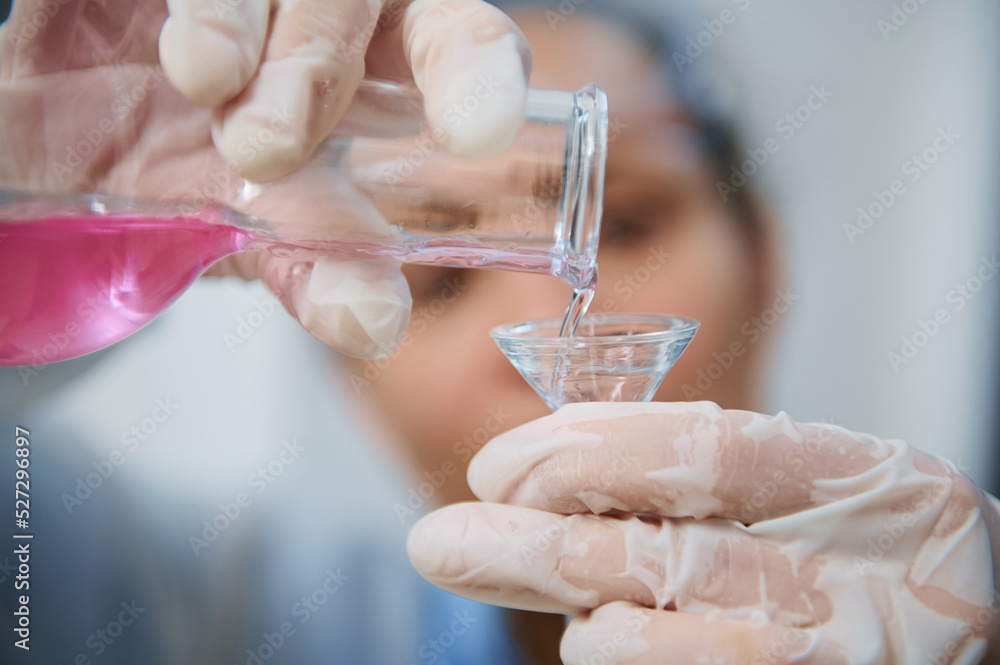Details: Gloved hands of blurred chemist scientist, pouring pink fluid ...