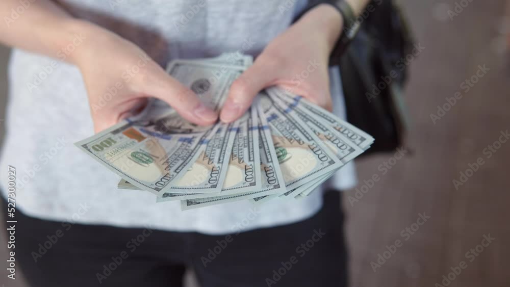 Counting money on the street. A woman counts a large amount of American ...