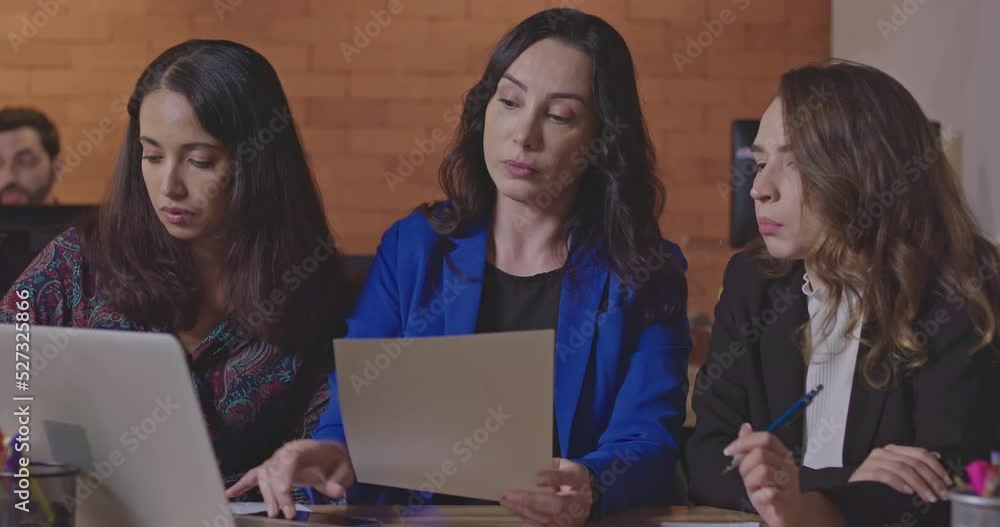 Women discussing work in front of laptop computer at corporate ...