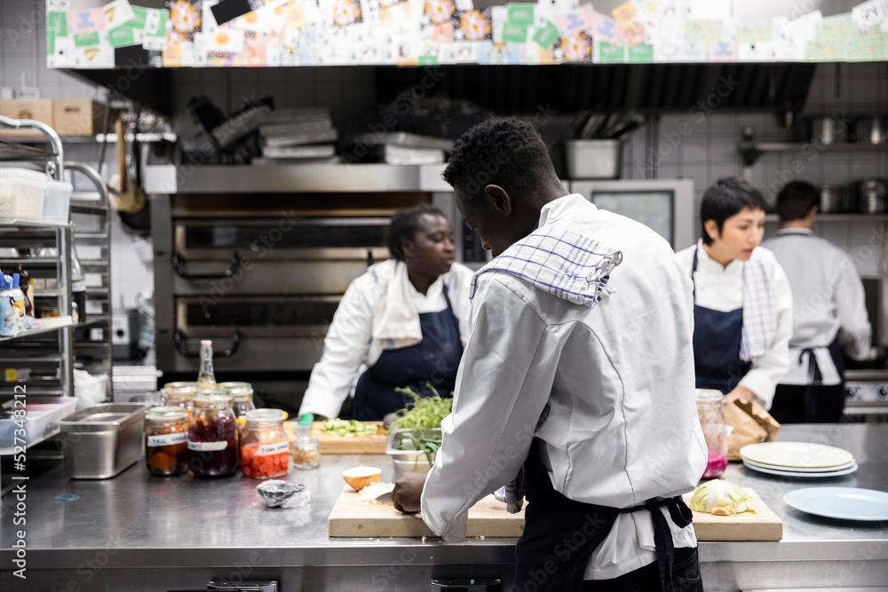 Multiracial chefs preparing food in kitchen of restaurant Stock Photo ...
