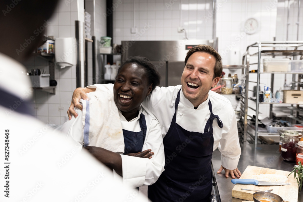 Happy chef with arm around female colleague in commercial kitchen Stock ...