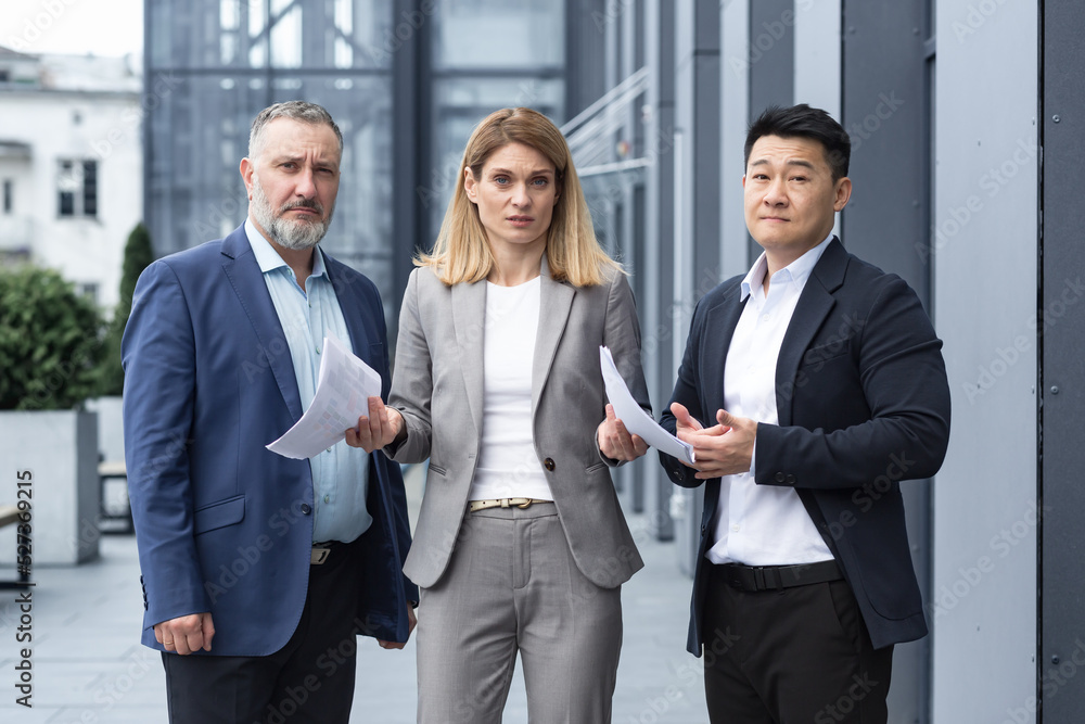 Frustrated female business boss with documents looking at camera, team ...