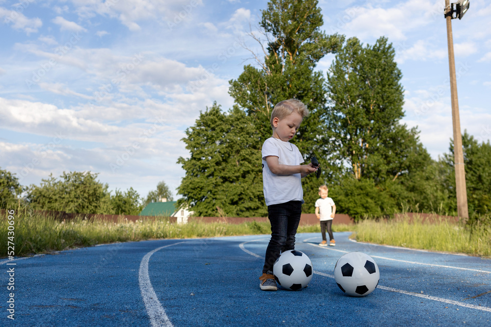 Twin brothers are playing on a walk with soccer balls.The twins are ...