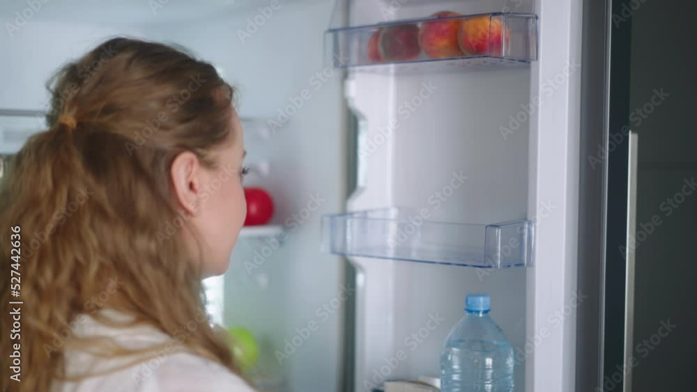 Woman putting groceries in new modern fridge. Young adult female ...
