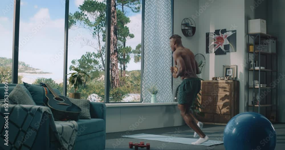 African american athlete doing workout at home, looking out the huge ...