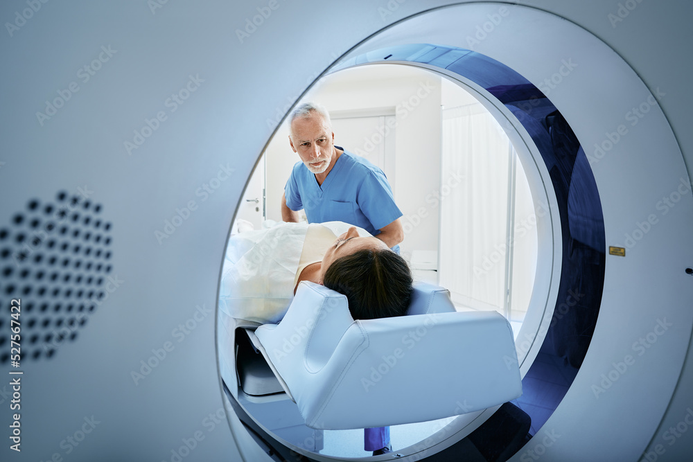 CT scan technologist overlooking patient in Computed Tomography scanner ...