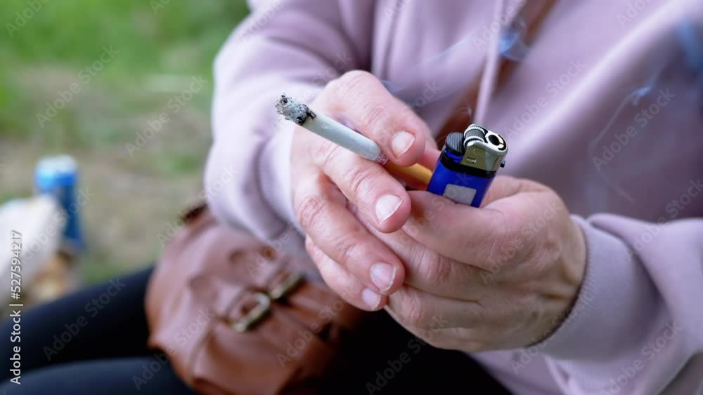 Woman Holding a Cigarette and a Lighter in Hands Sitting in Nature on ...