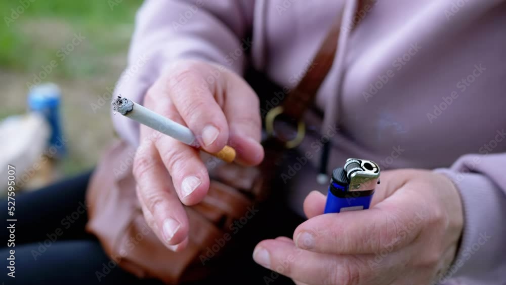 Woman Holding a Cigarette and a Lighter in Hands Sitting in Nature on ...