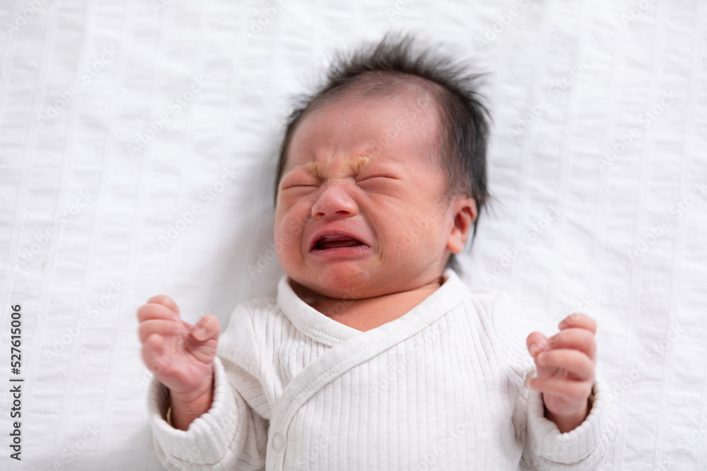 Crying and angry Newborn baby boy lying on white bed at home.Infant ...