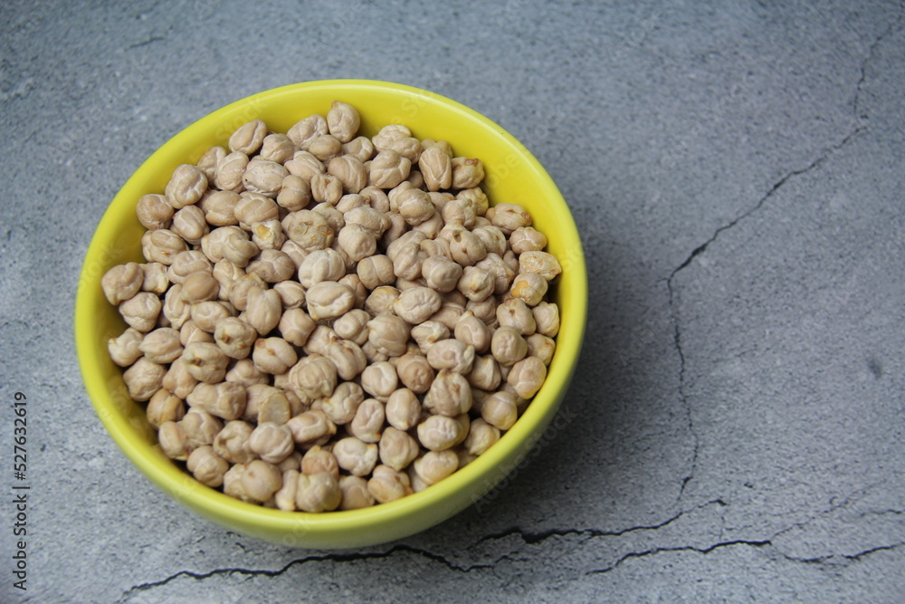 Chickpeas (Cicer arietinum) in a yellow crockery bowl on a rustic gray ...