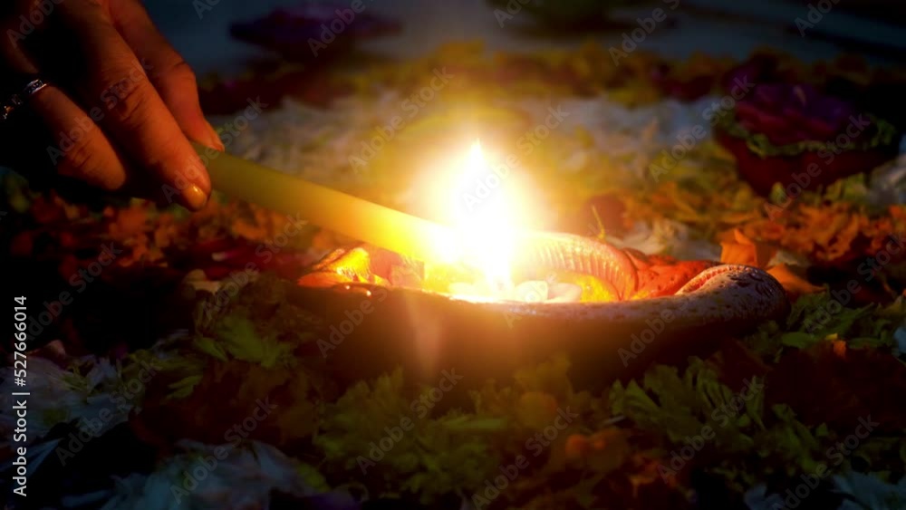 soft filter shot of person lighting diya oil lamp with a lit candle set ...