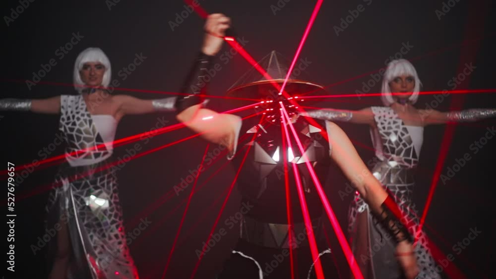 Man imitating fight spinning with red laser beam swords as women moving ...