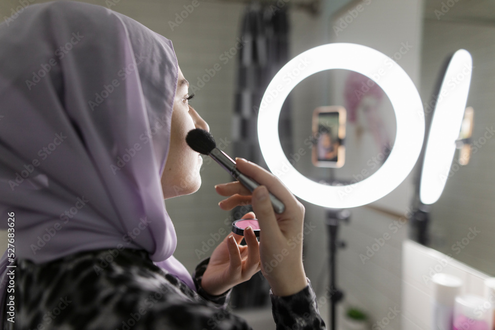 Female influencer in hijab applying makeup for tutorial Stock Photo ...