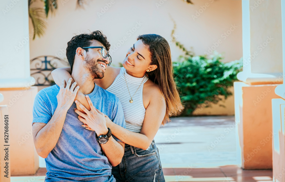 Girl hugging her boyfriend from behind. Smiling woman hugging her boyfriend from behind while he ...