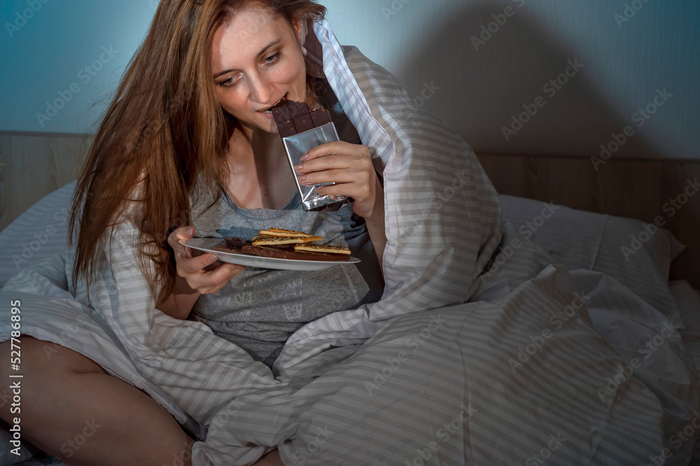 Woman late-night snacking in bed at home waking up hungry at night ...