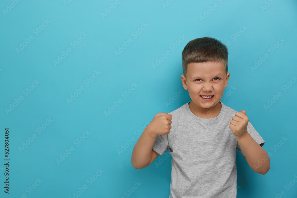 Angry little boy on light blue background, space for text. Aggressive ...