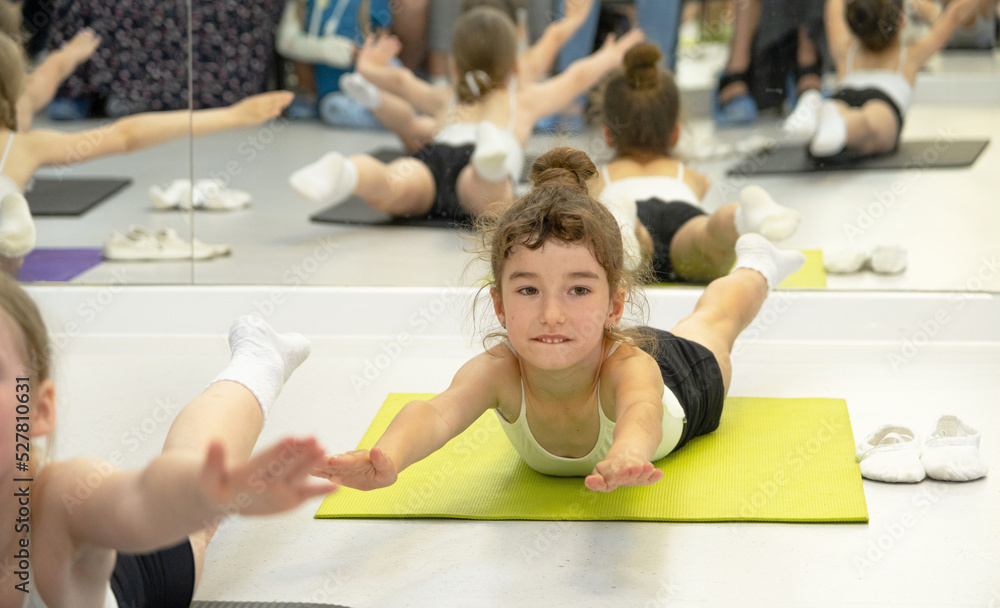 Child trains in gym on the mat, does stretching exercises and abs ...