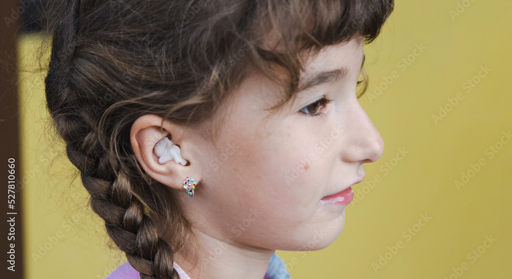 Girl with a warming therapeutic cotton swab in the ear with a sad and ...