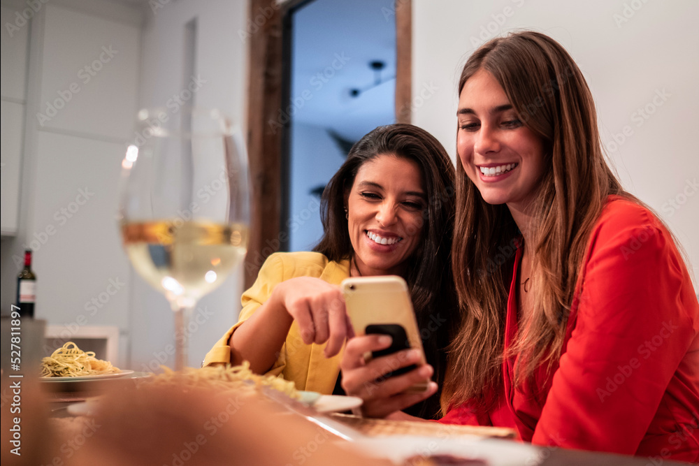 Overjoyed female friends using cellphone at party Stock Photo | Adobe Stock