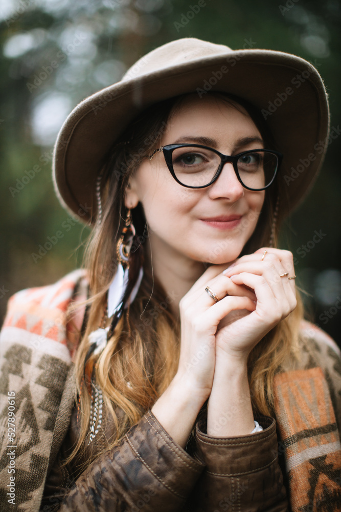 A boho-style girl with feathers in her hair, a brown hat, a leather ...