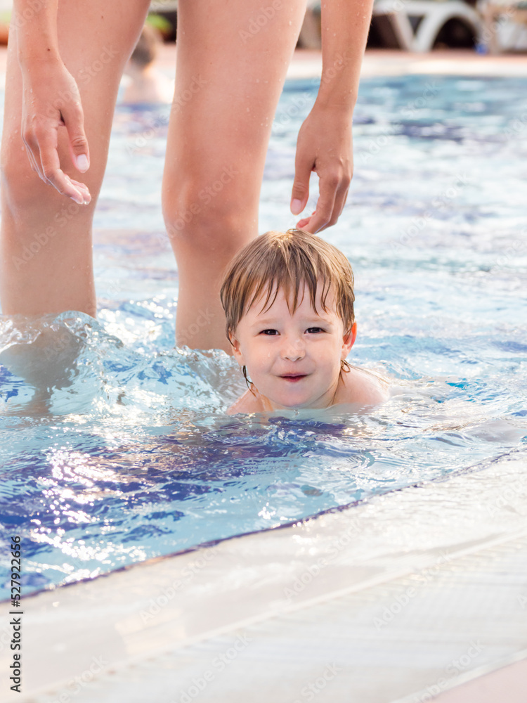 Toddler floats in paddling pool. Teaching children to swim from early ...