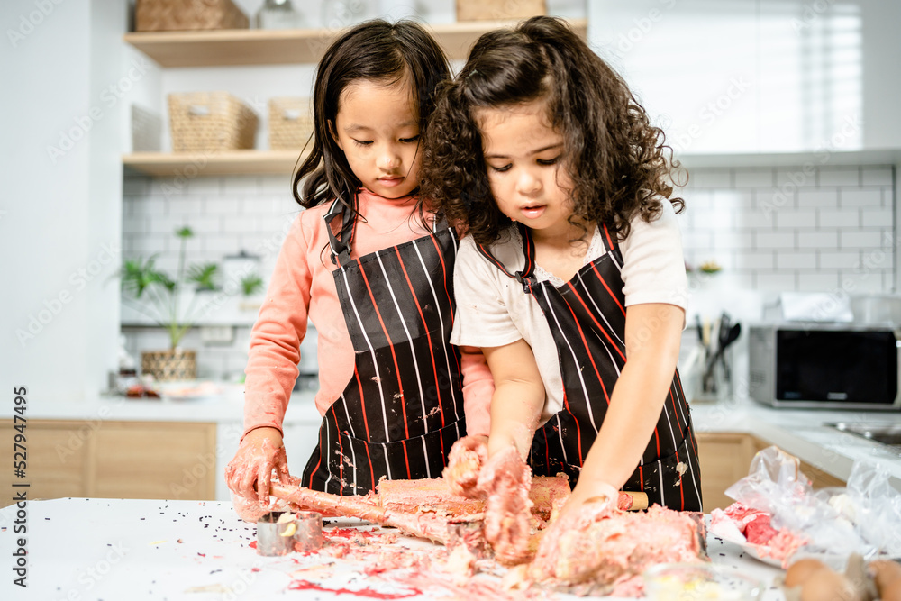 Two diverse kid girls having fun cooking cake bakery together in the ...