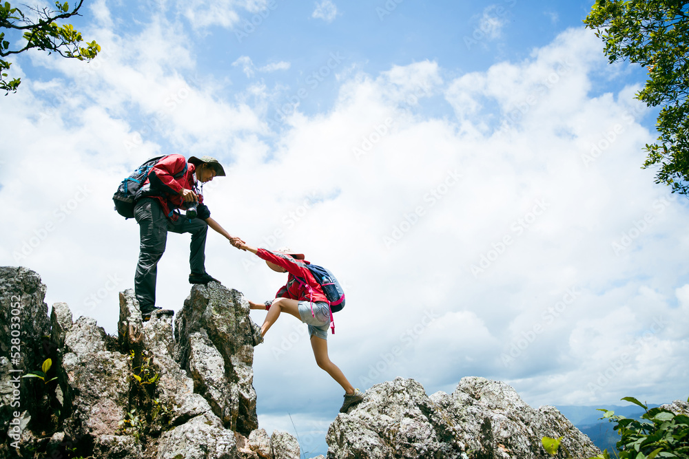 Person hike friends helping each other up a mountain. Man and woman ...