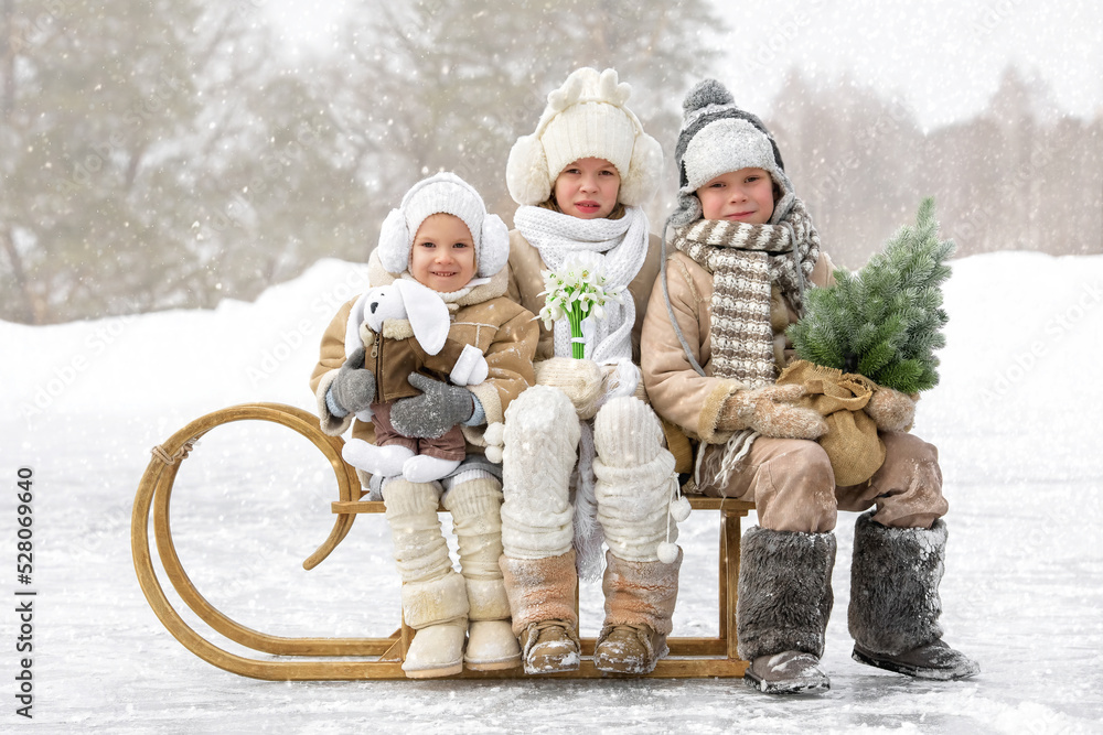 Happy kids play outside in winter. Children ride in the snow on an old ...