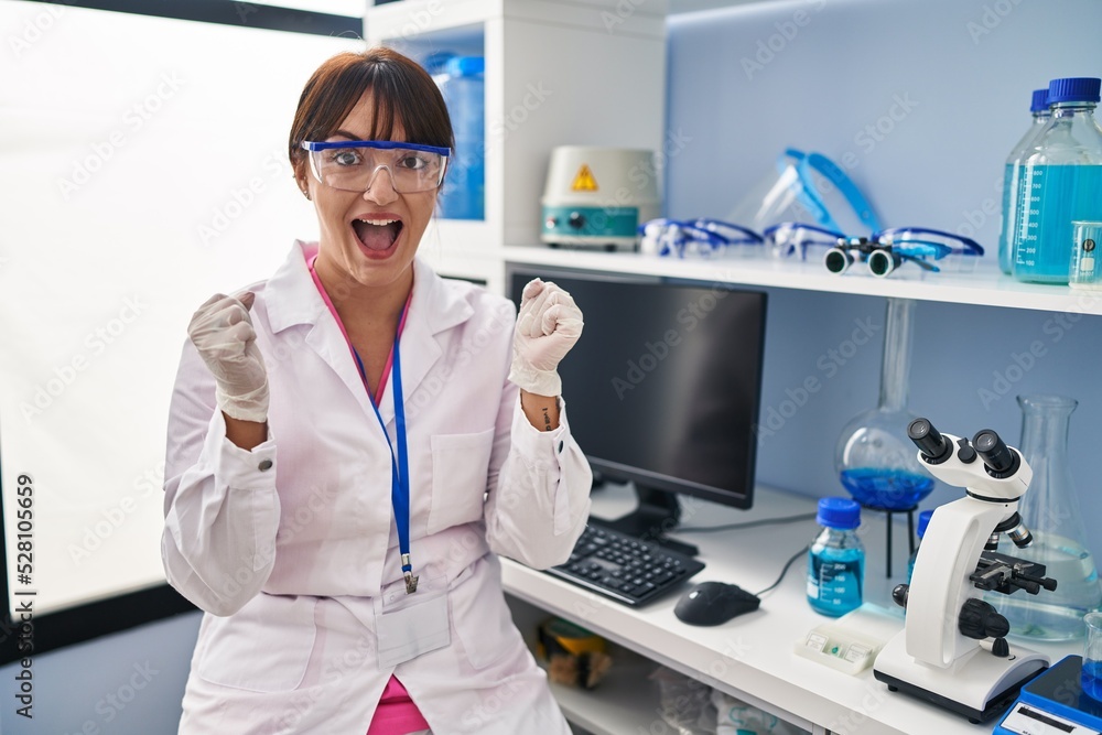 Young brunette woman working at scientist laboratory celebrating ...