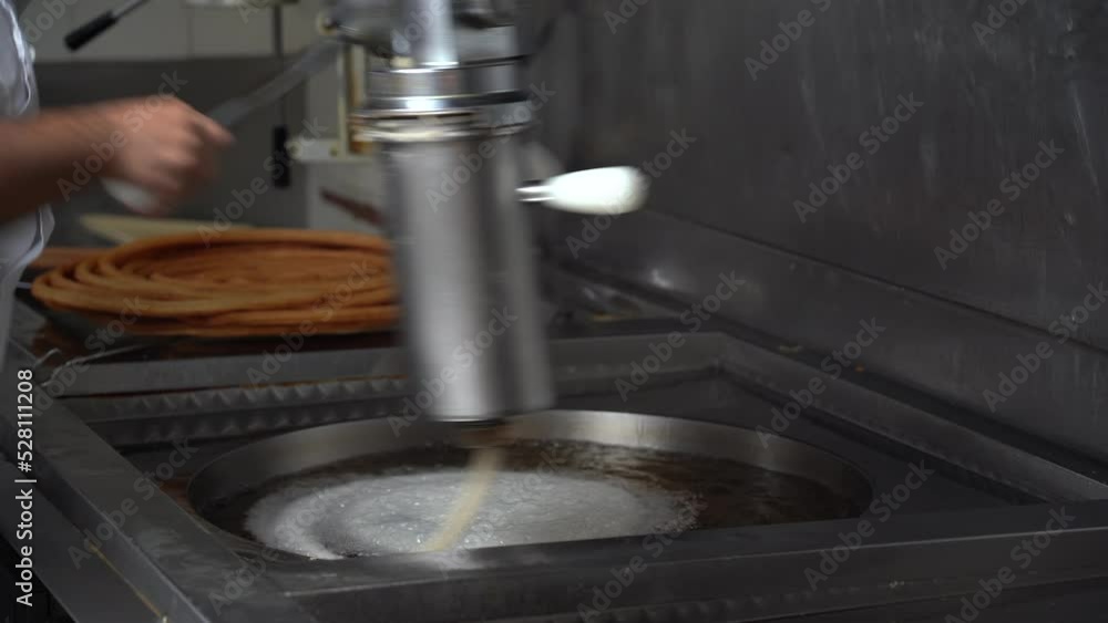 Churrero haciendo roscas de churros en una gran freidora de pastelería ...