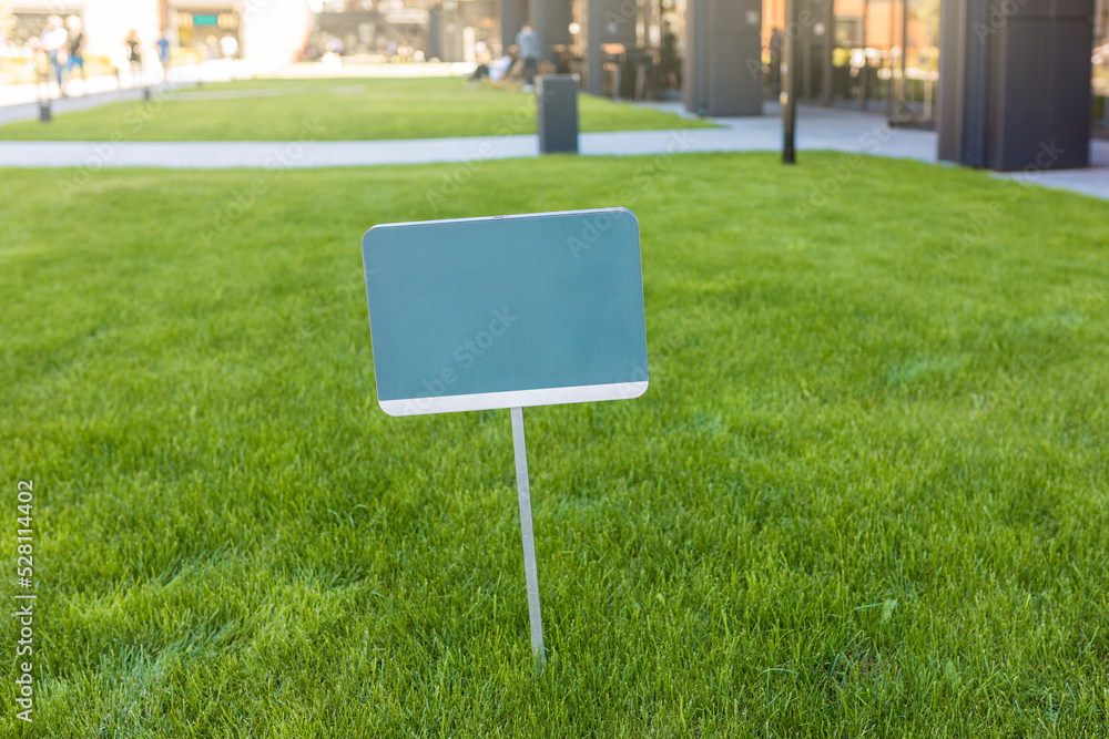 Closeup gray metal sign at green grass background, nameplate with a ...